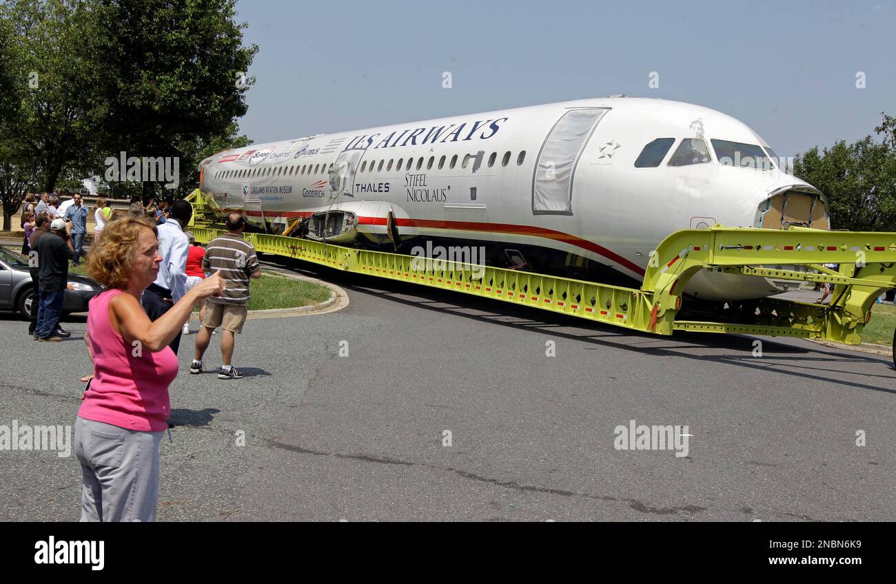 People look on as the fuselage of US Airways flight 1549 as it arrives ...