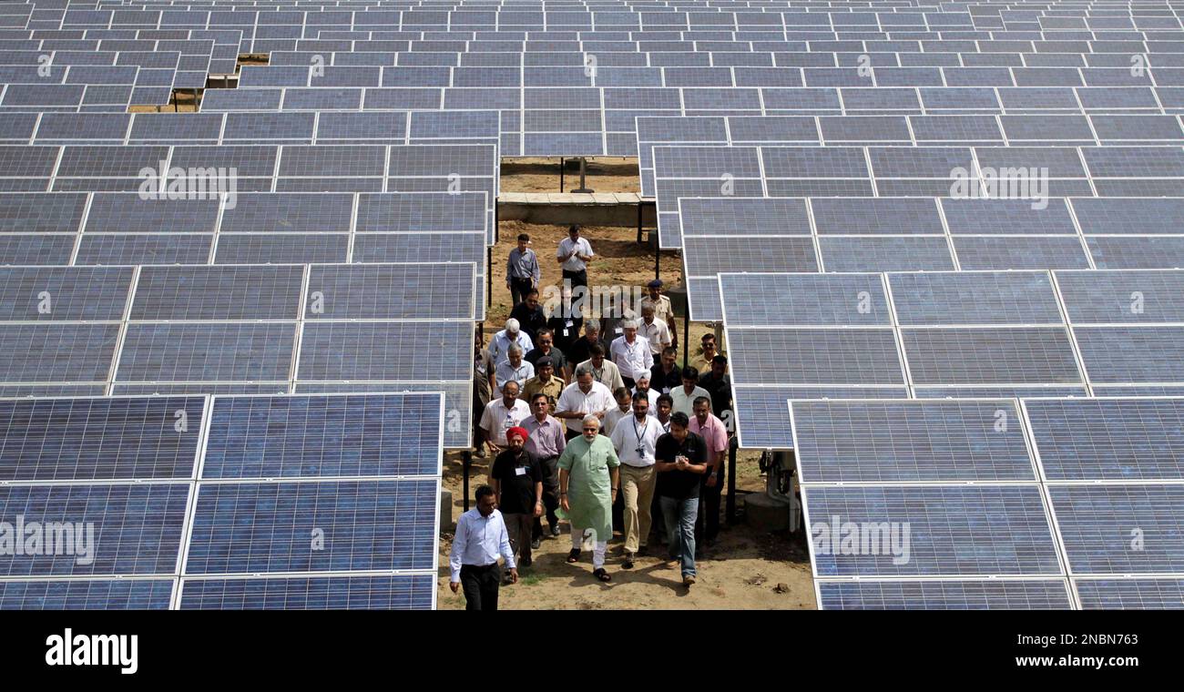 Gujarat Chief Minister Narendra Modi, center, walks among solar panels ...