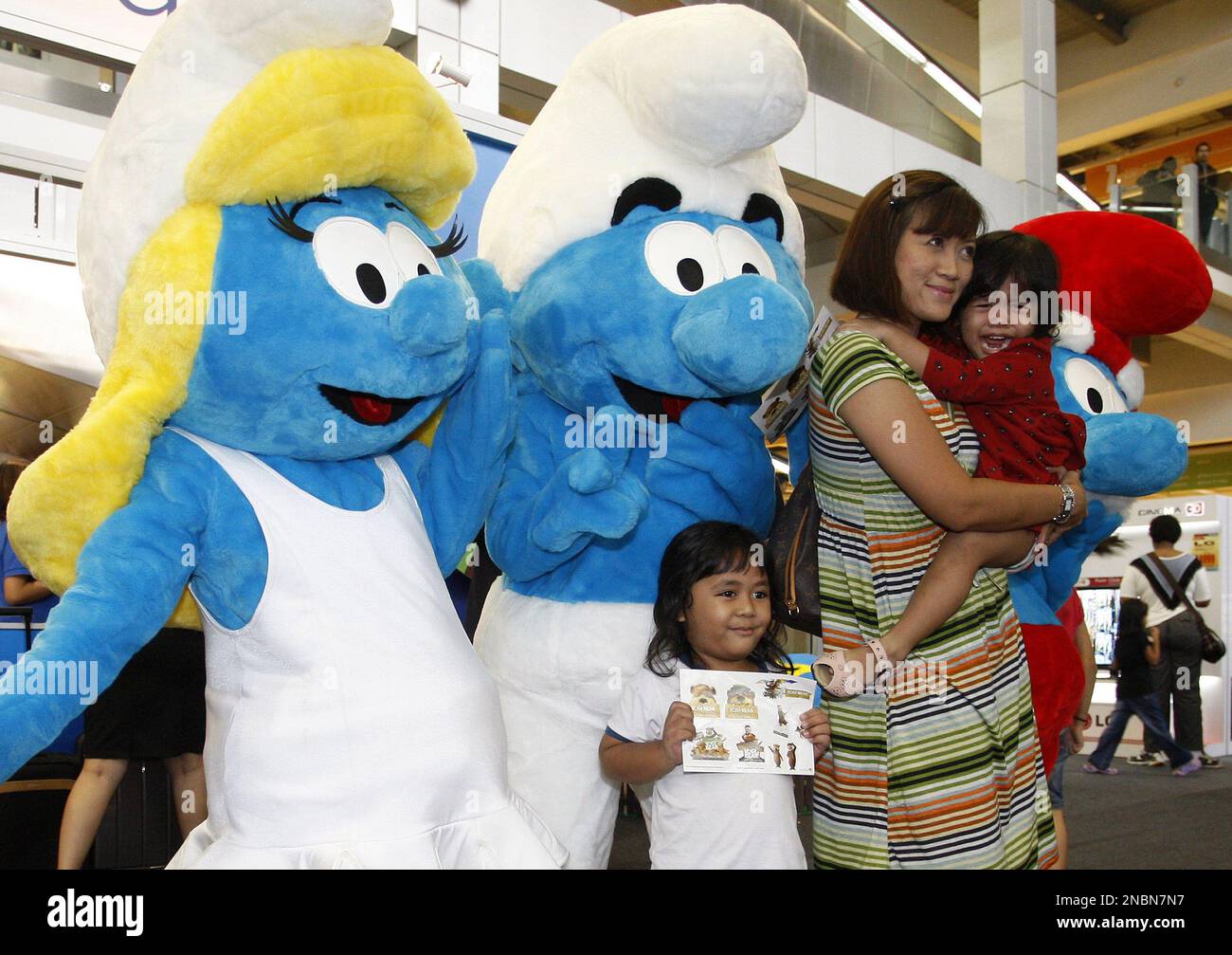 Shoppers pose for a photo with "The Smurfs" characters at a shopping ...