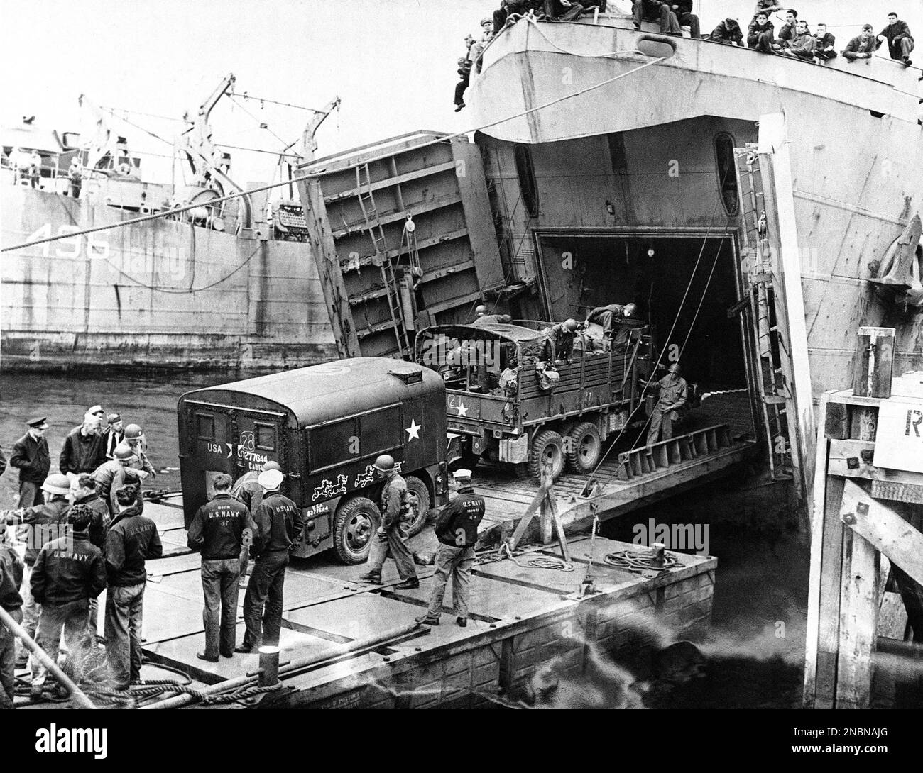 A big U.S. army field kitchen is rolled up the open bow of an LST ...