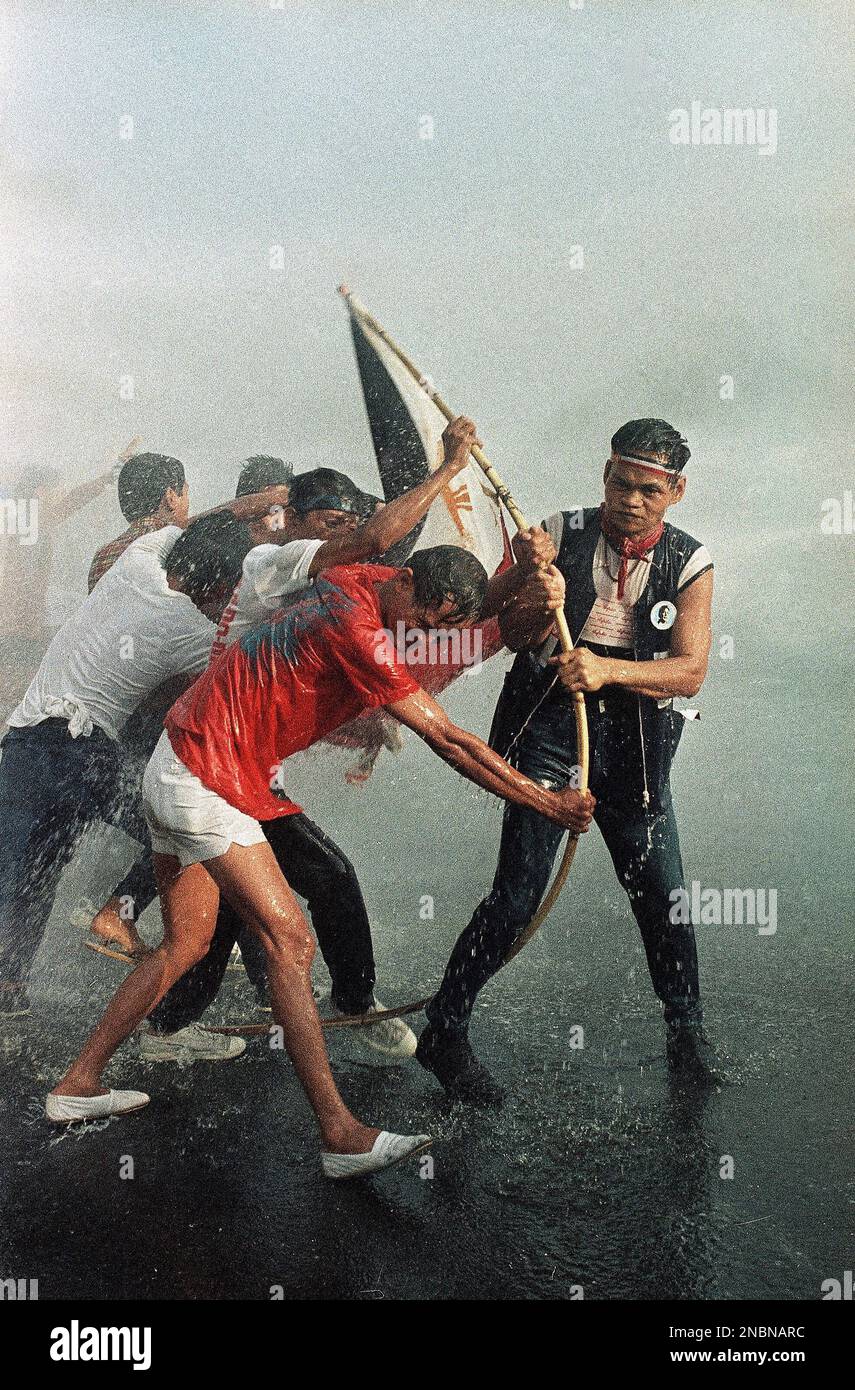 Loyalists for ousted President Ferdinand Marcos hold onto a bamboo pole ...