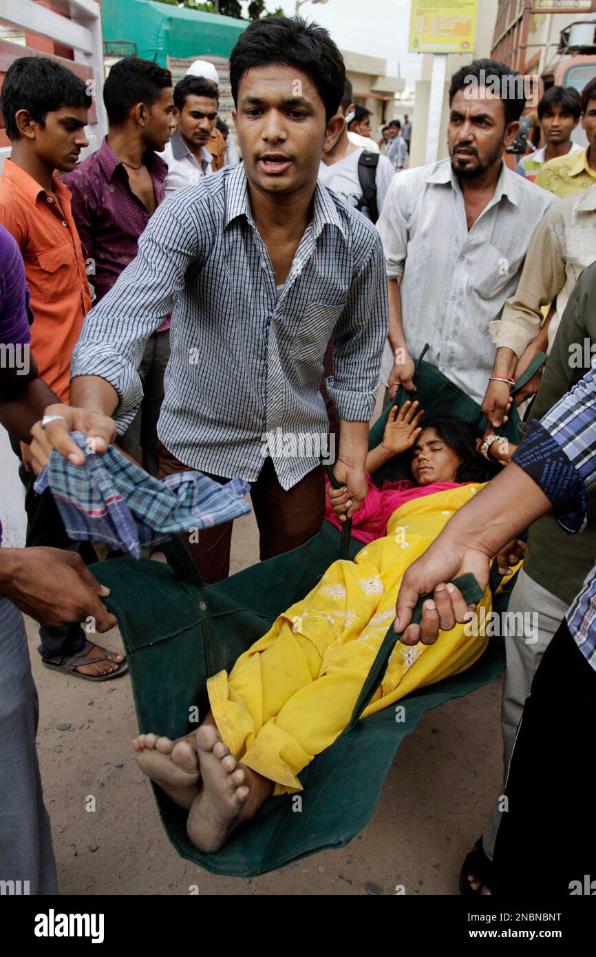 Volunteers carry a woman injured in an accident to a hospital in Dholka ...