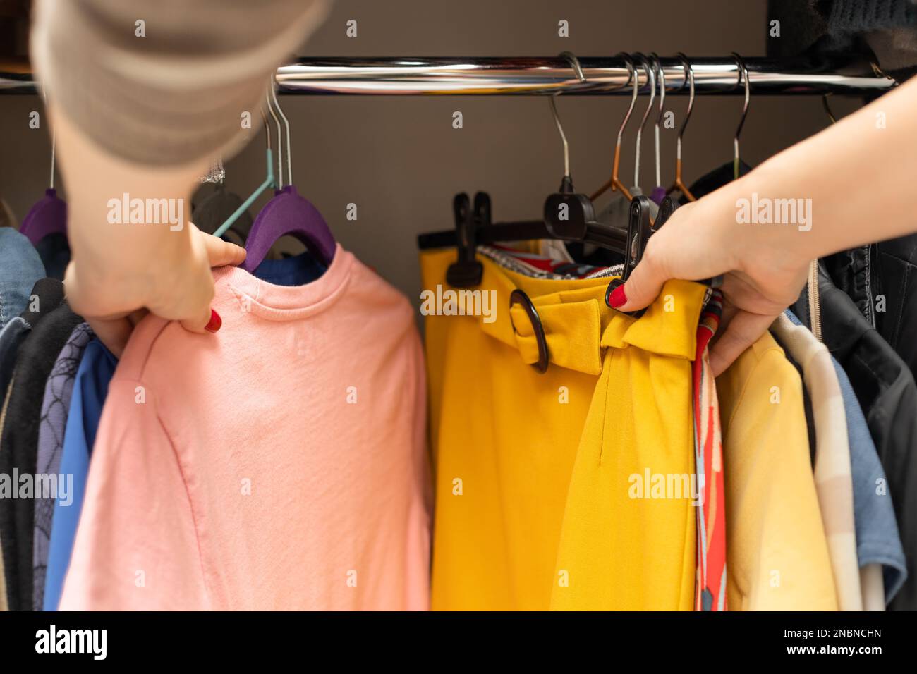 a woman near the closet chooses a T-shirt for her to wear. woman trying ...