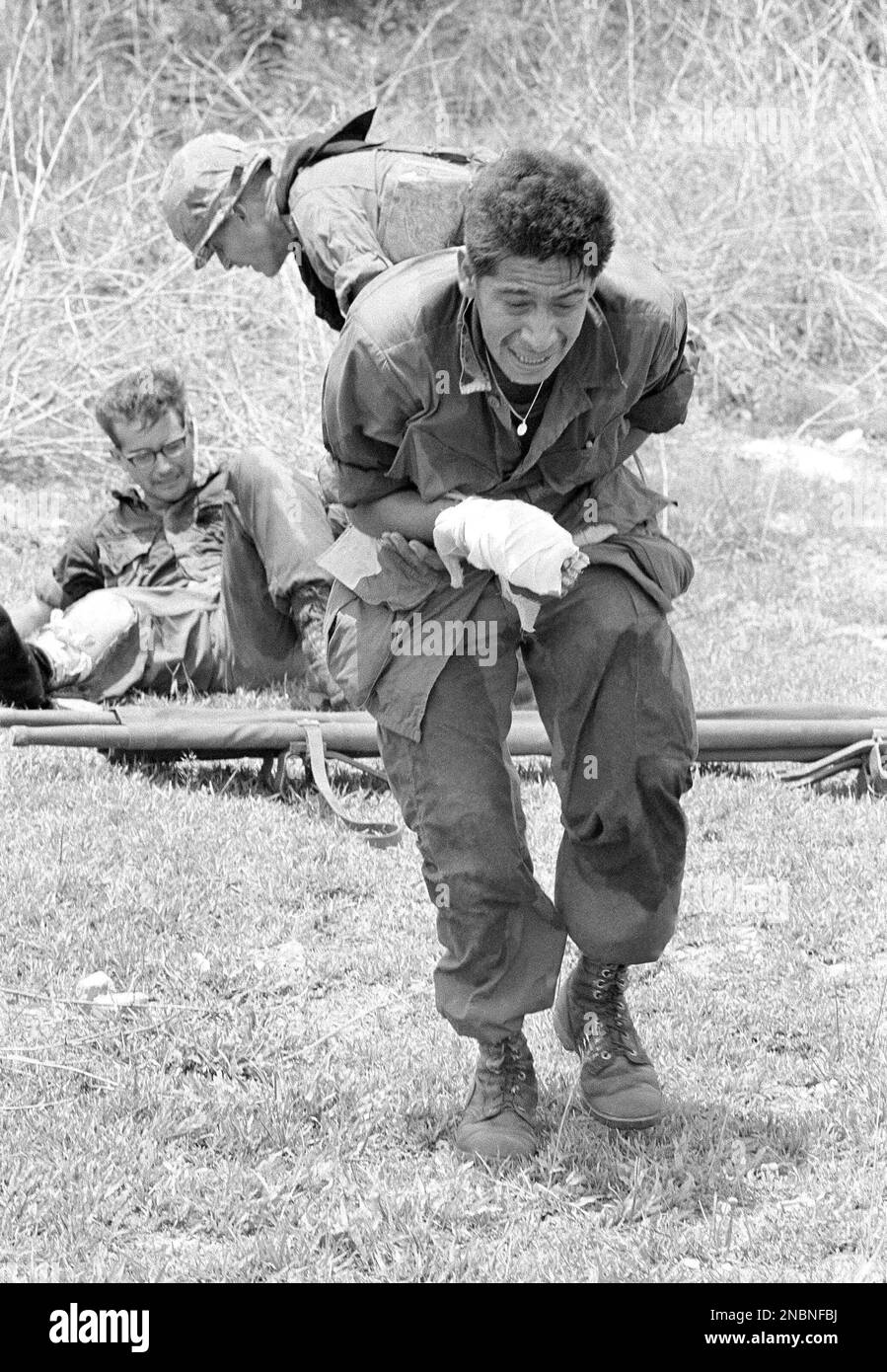 An American soldier grimaces as he holds arm wounded during encounter ...
