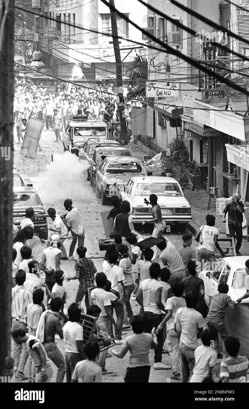 Supporters of President Corazon Aquino (foreground) throw back stones ...