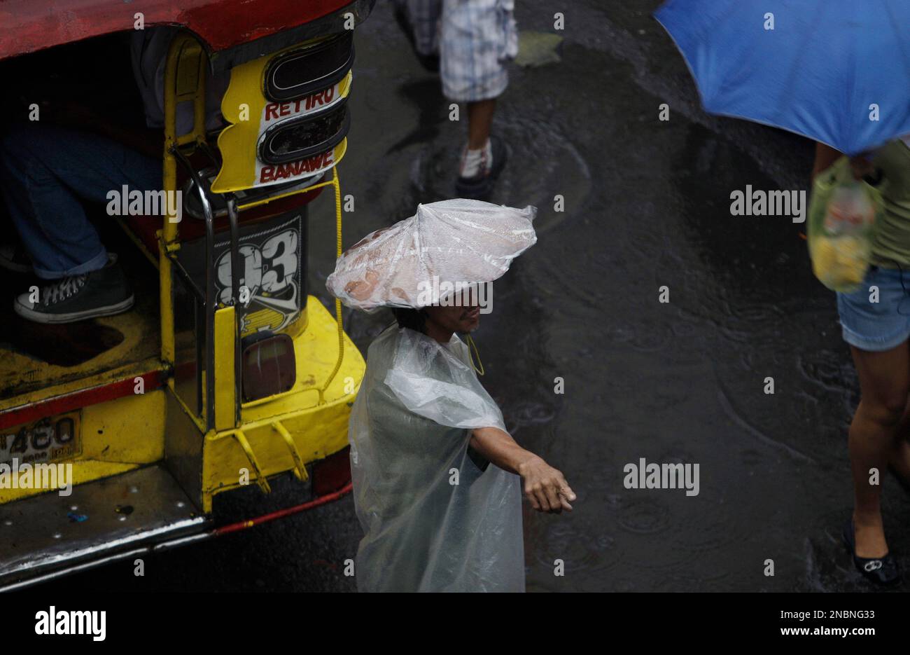 A Filipino man covered in plastic sheets calls for passengers during a ...