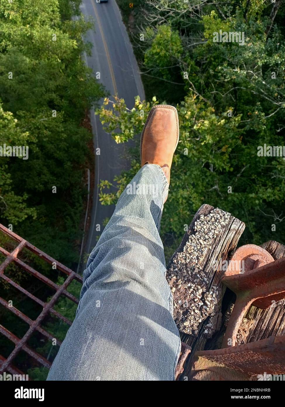 A view of a foot leaning over cliff above a road Stock Photo - Alamy