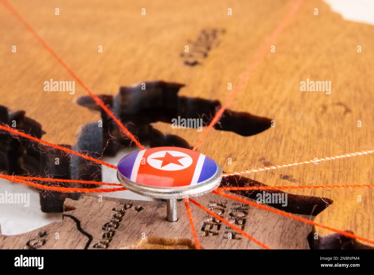 North Korea flag on the pushpin and red thread on the wooden map, close ...