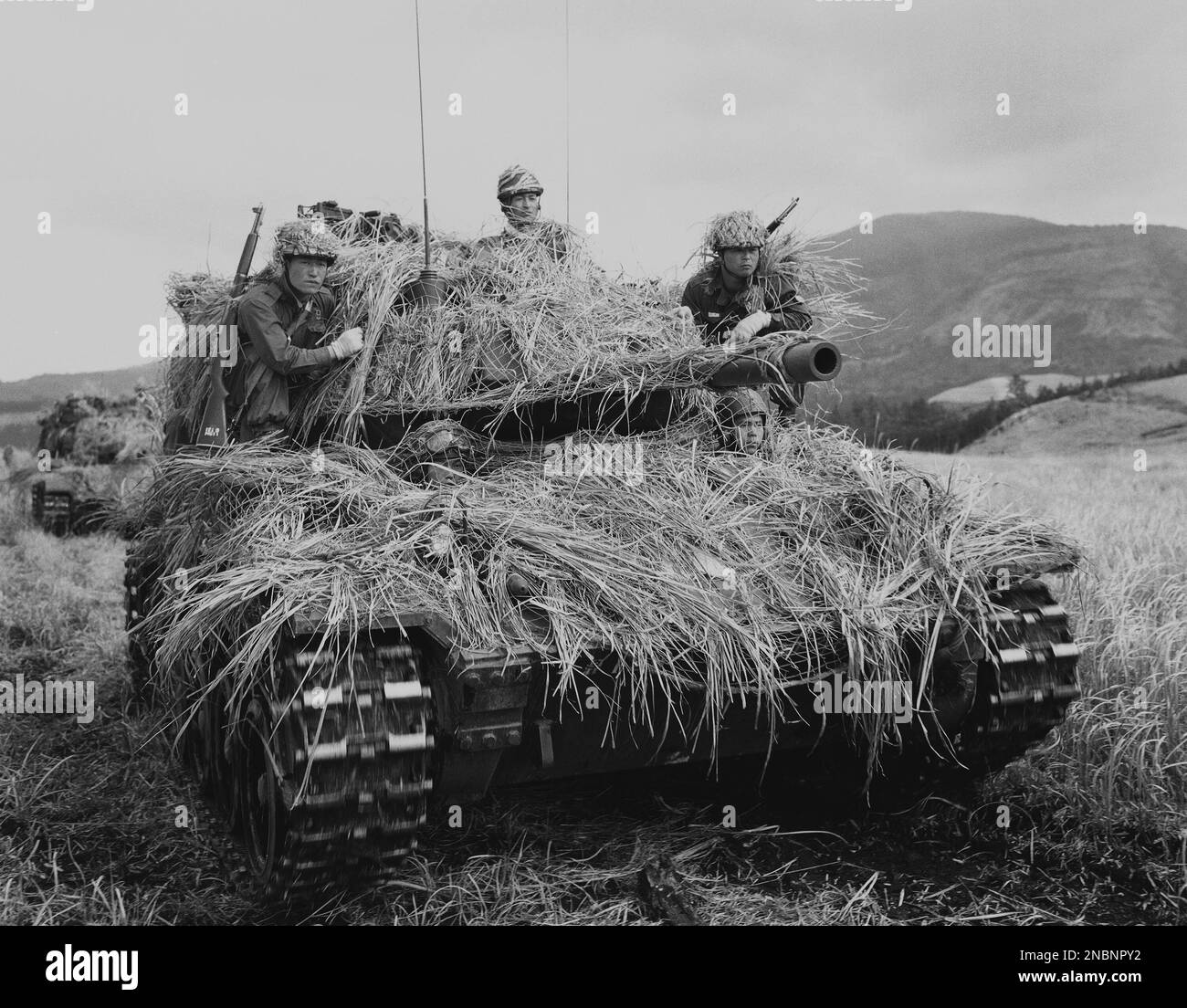 Infantrymen ride atop a camouflaged tank as they move out on the ...