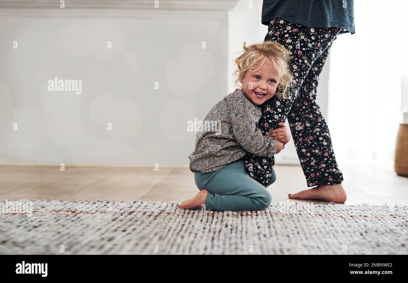 Happy, child clinging to leg of woman and playful fun and smile on ...