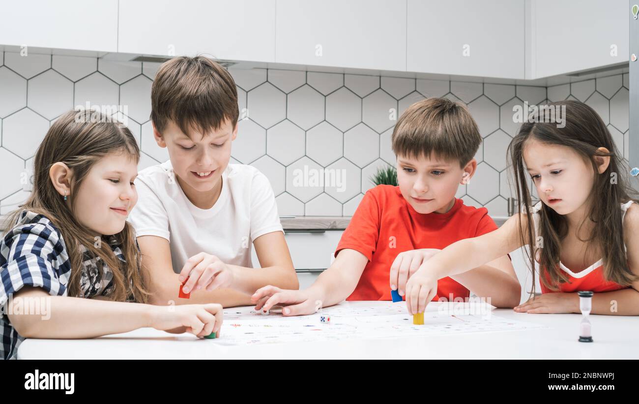 Funny little school friends play board game on paper map with dice and ...