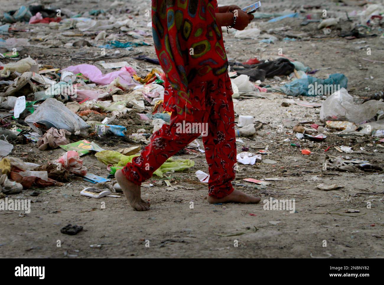 An Afghan girl walks with bared feet at a garbage site on the World ...
