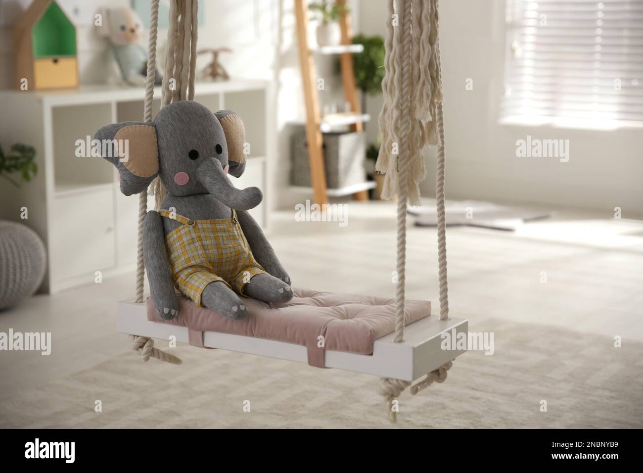 Beautiful swing with toy elephant in room. Stylish interior design ...