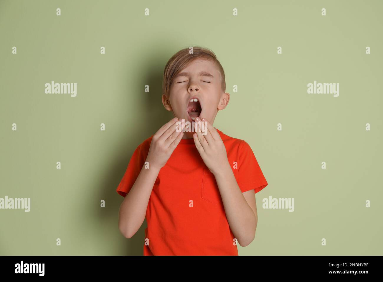 Portrait of sleepy boy yawning on light background Stock Photo - Alamy