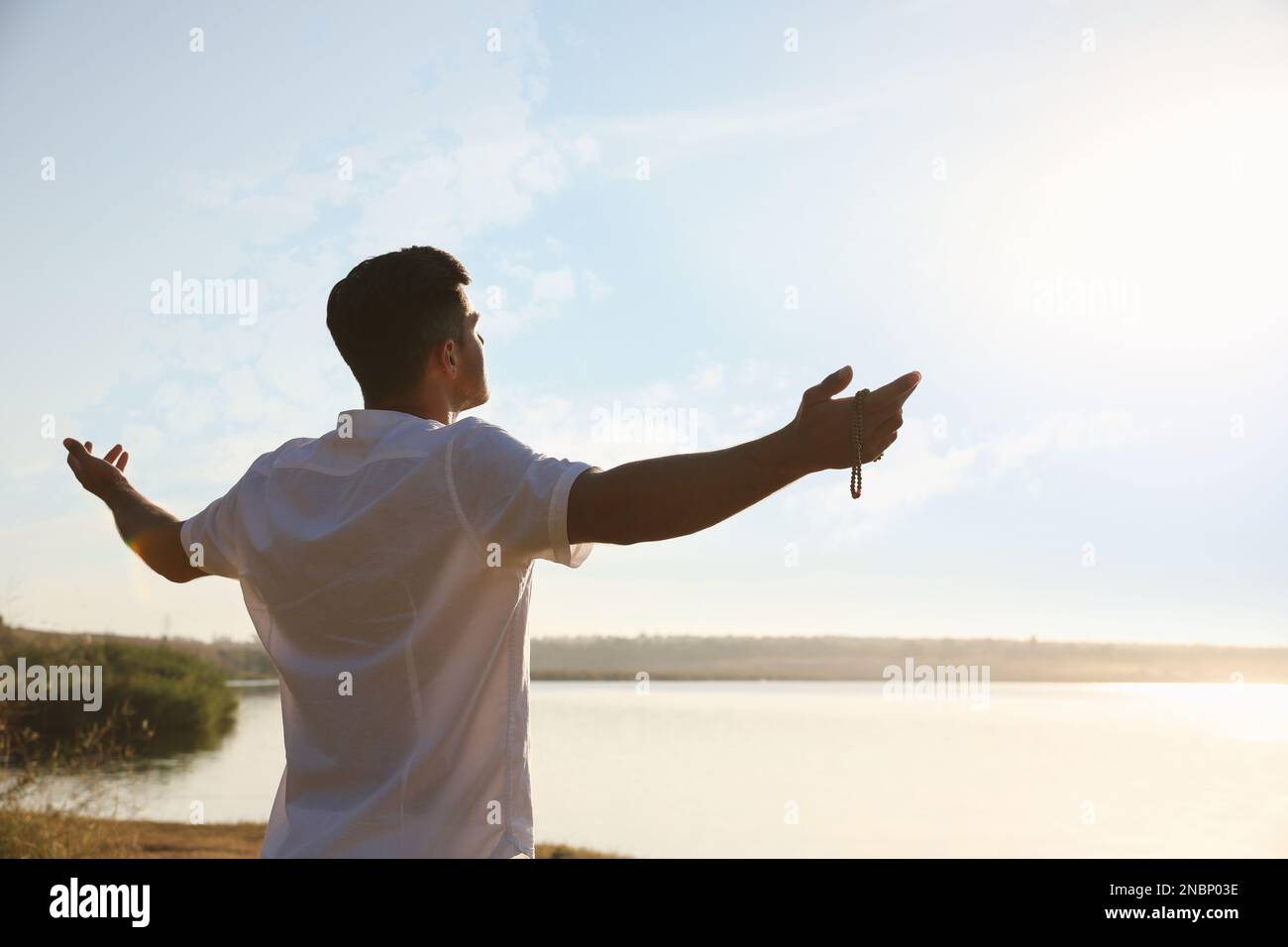 Man near river at sunset, back view. Nature healing power Stock Photo ...