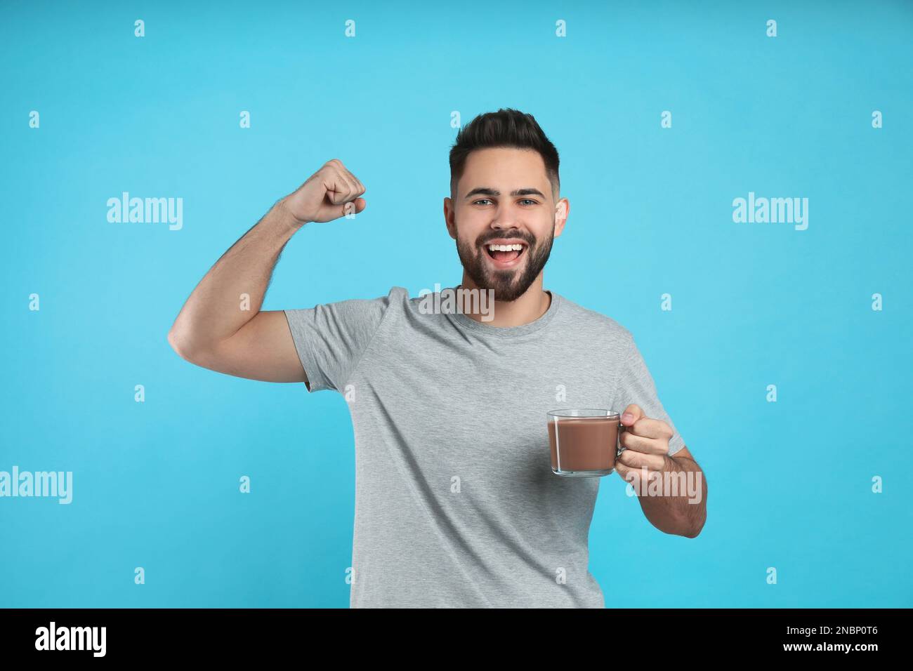 Young man with glass cup of chocolate milk showing his strength on ...