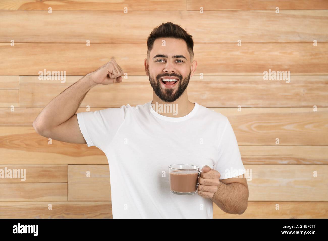 Young man with glass cup of chocolate milk showing his strength on ...