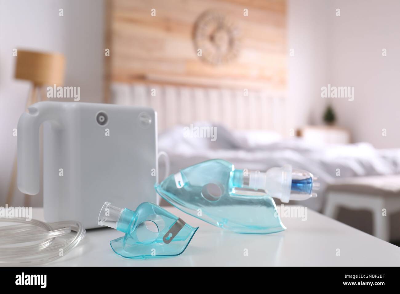 Modern nebulizer with face masks on white table indoors, space for text ...