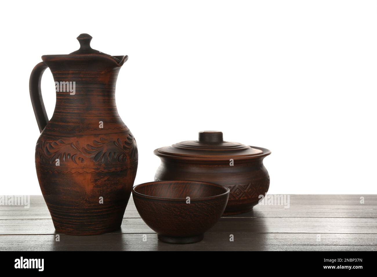 Different clay dishware on wooden table against white background Stock ...