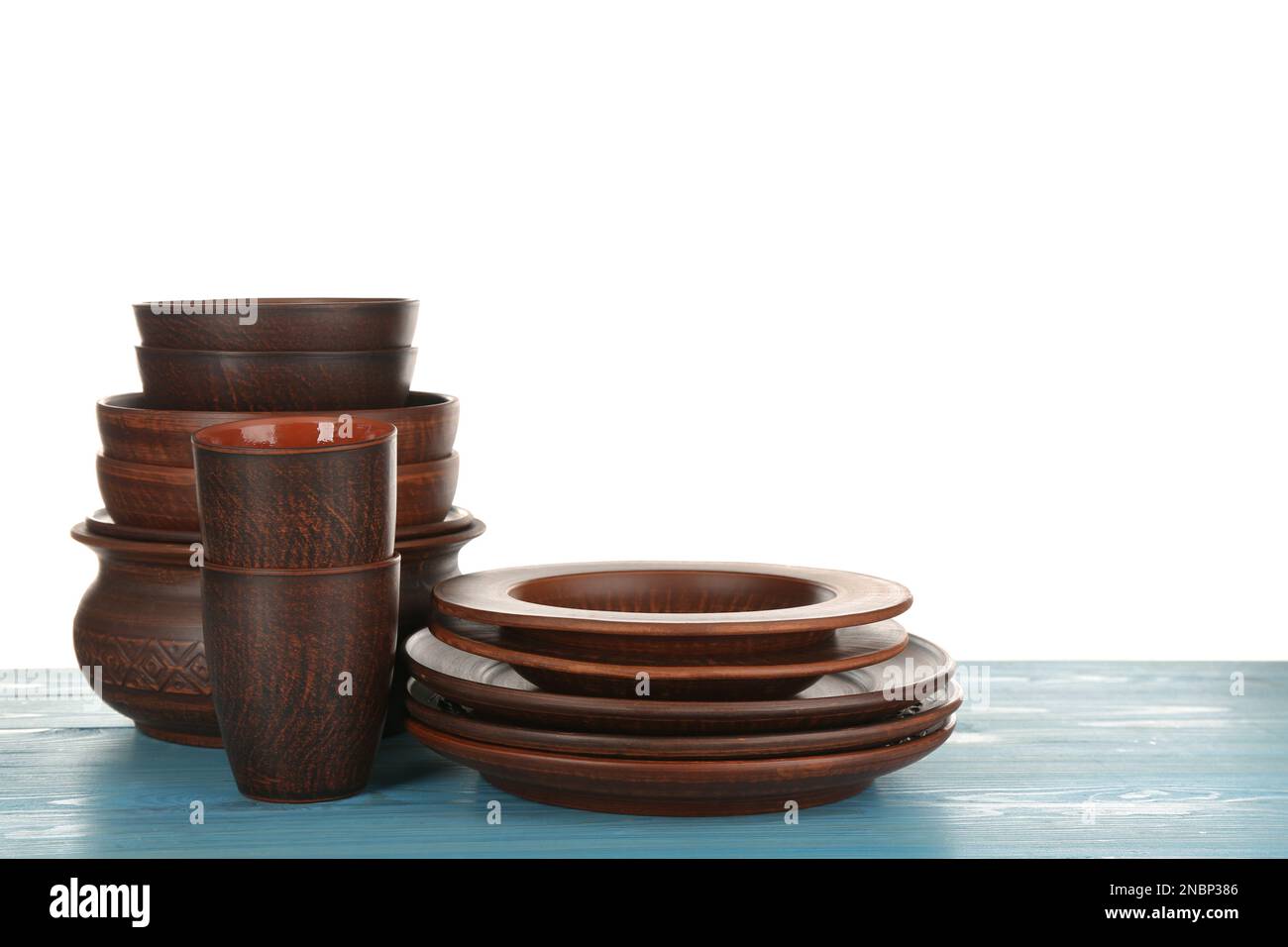 Different clay dishware on light blue wooden table against white ...