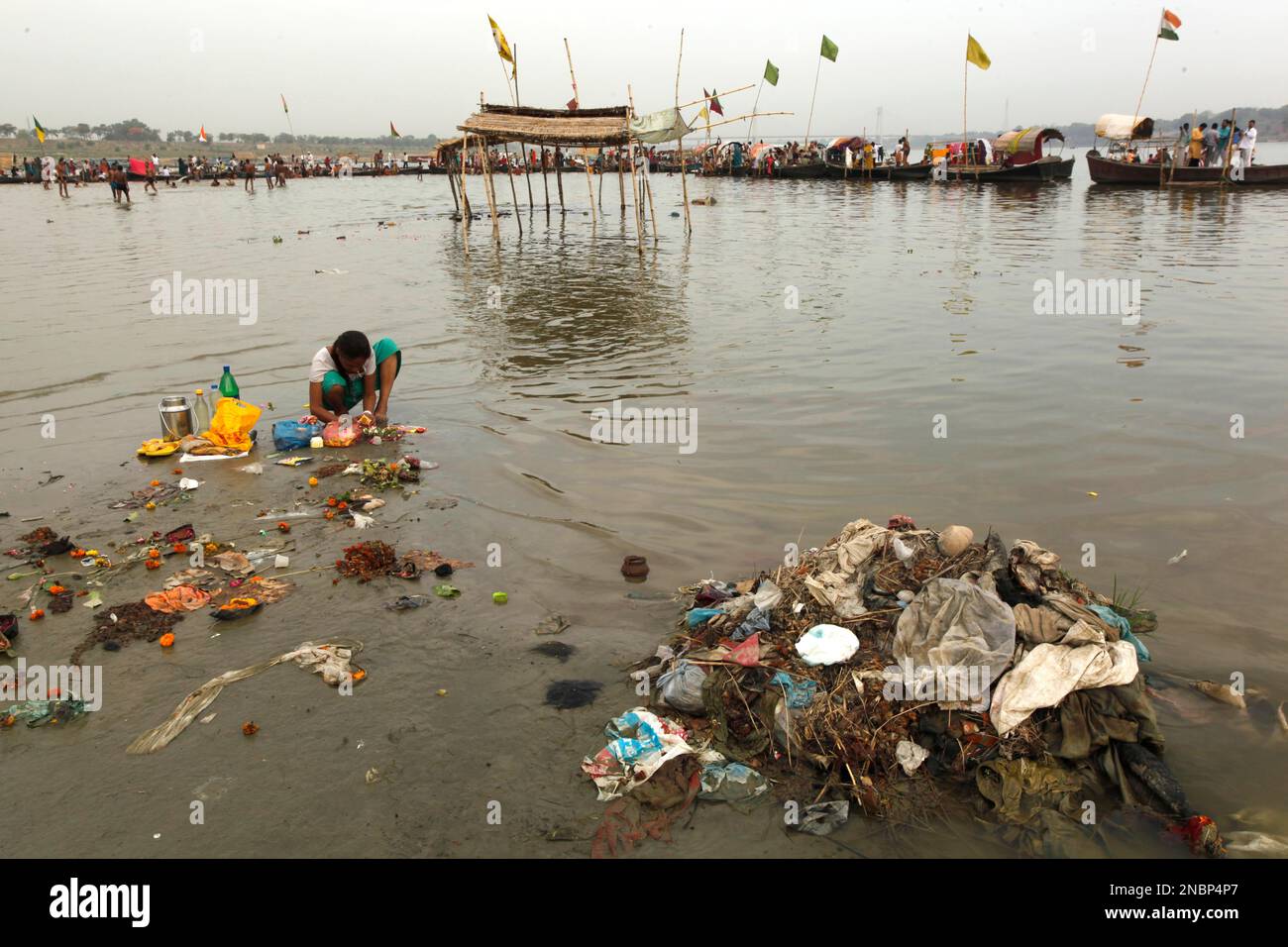 A Hindu devotee prays on the banks of the river Ganges next to a ...