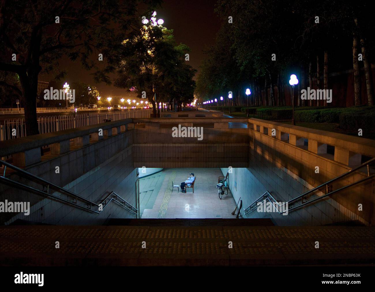 A Chinese policeman sits on a chair at an underpass tunnel in the dawn ...