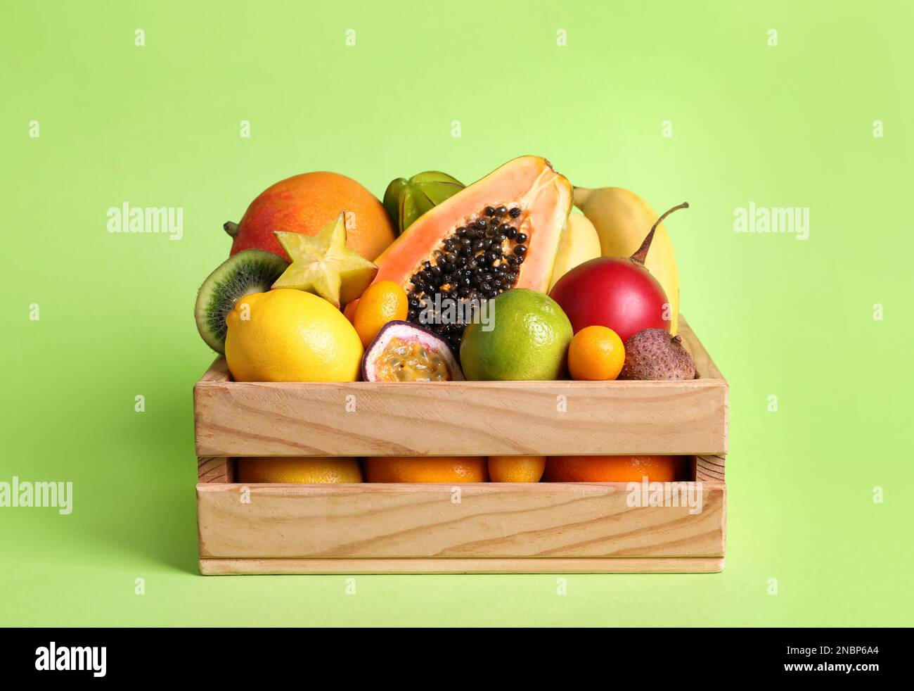 Different tropical fruits in wooden box on green background Stock Photo ...