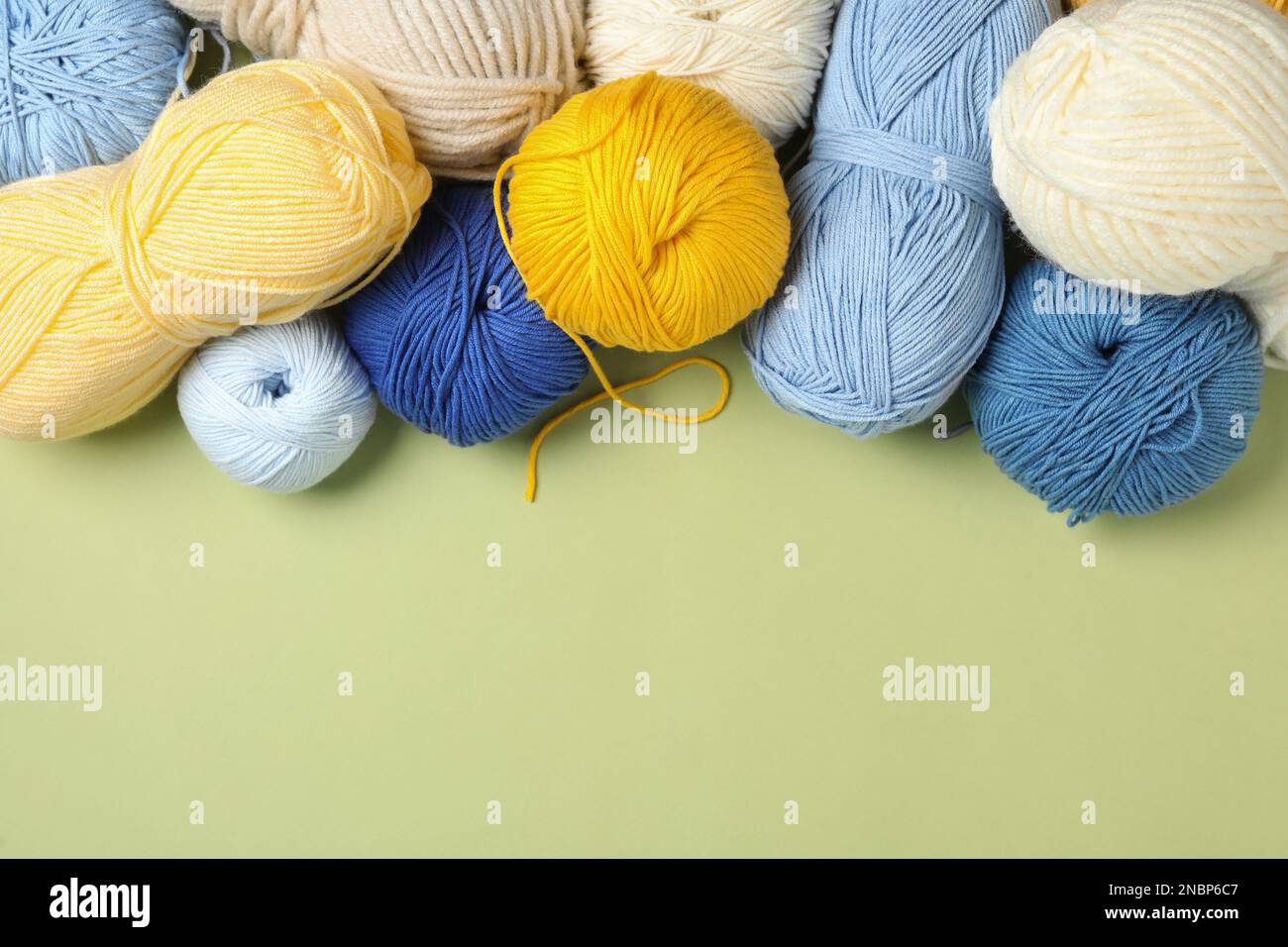 Soft woolen yarns on green background, flat lay. Space for text Stock ...