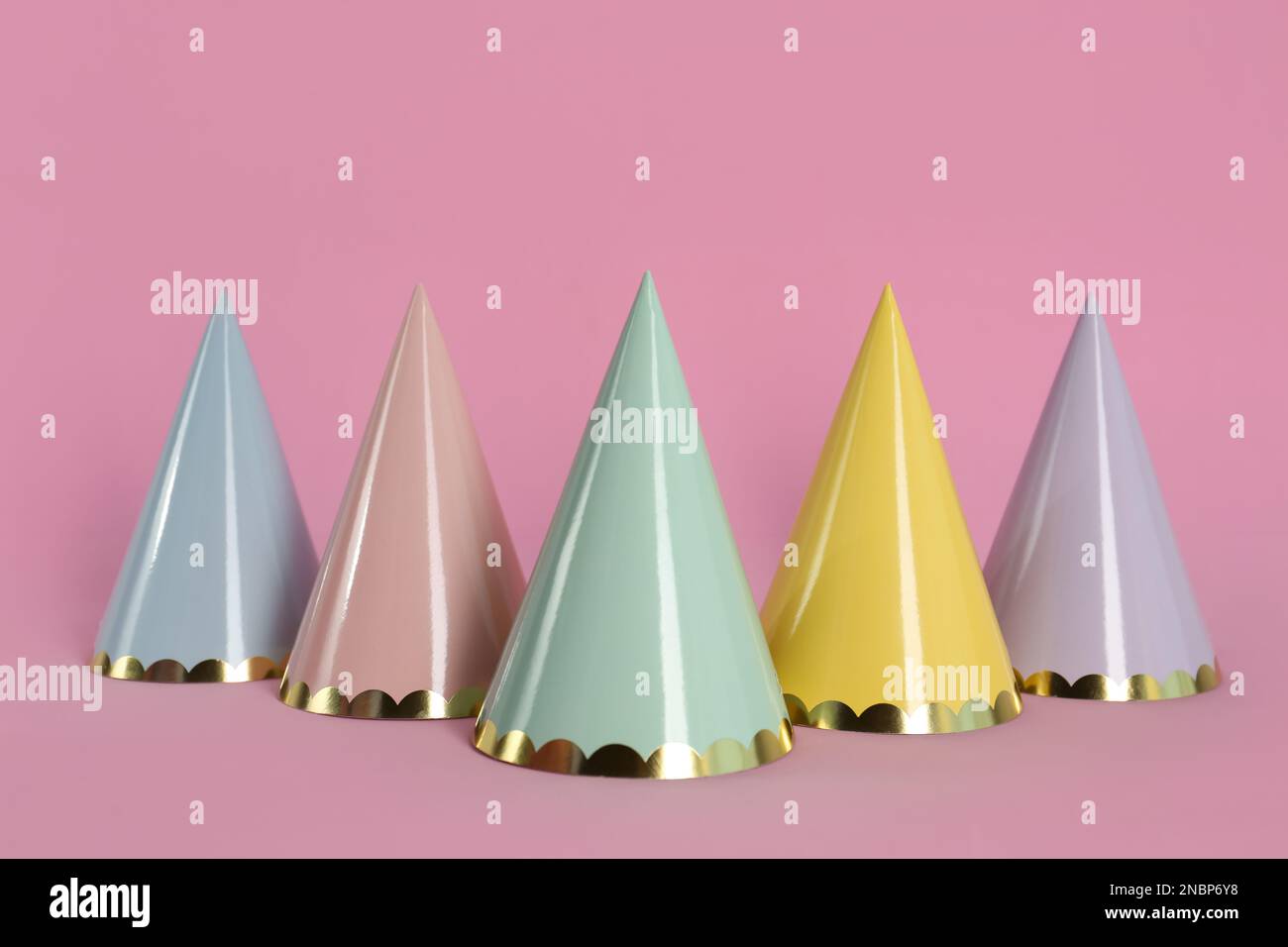 Different colorful party hats on pink background Stock Photo - Alamy