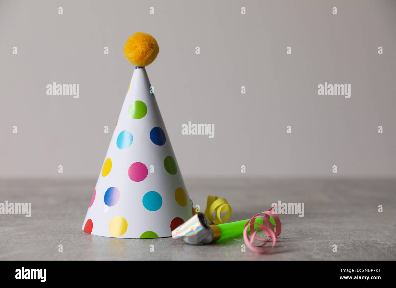 Birthday party hat, horn and serpentine streamers on grey table Stock ...