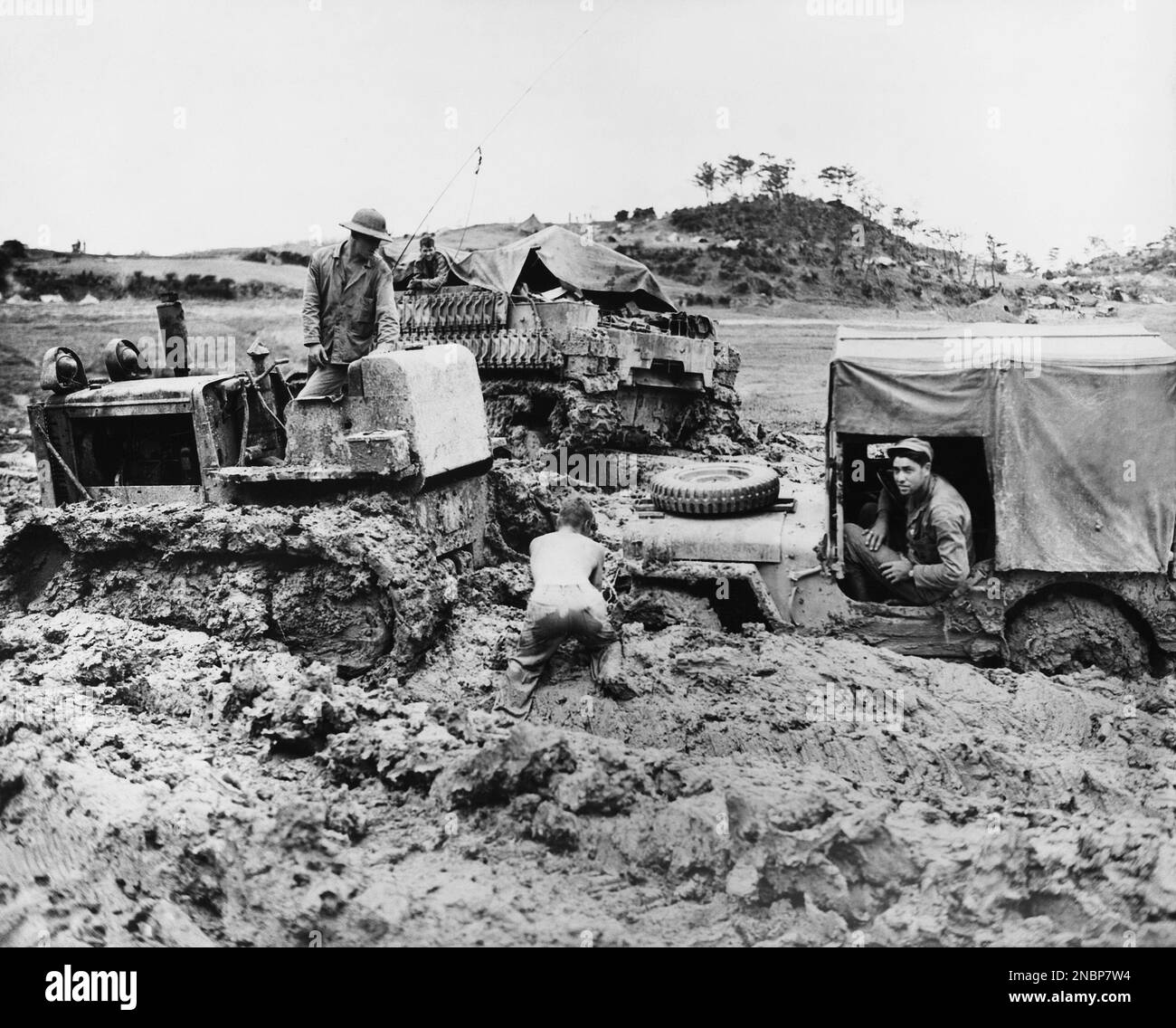 A tractor is coupled to a Marine Corps ambulance-jeep as steps are ...