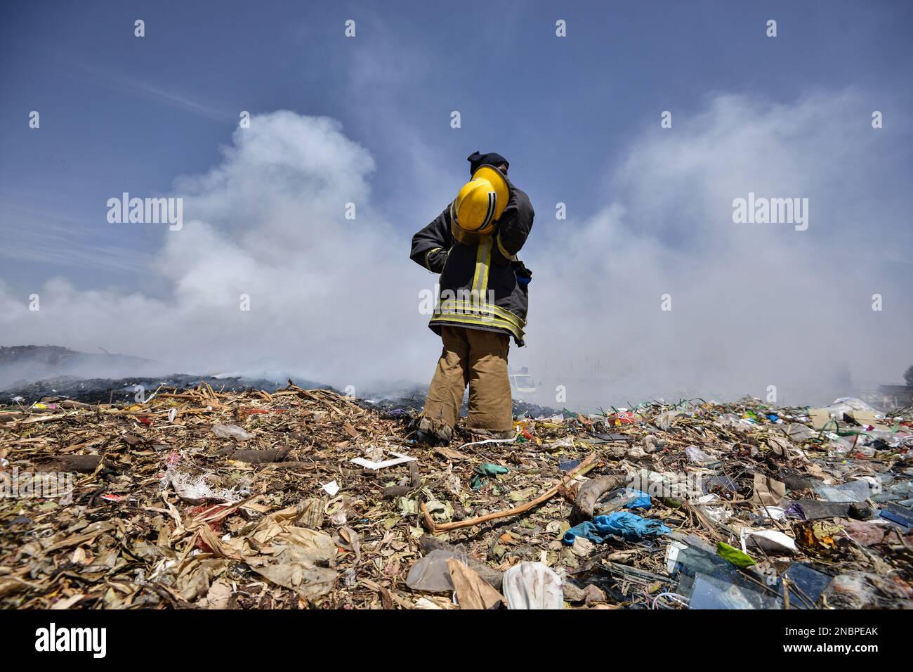 A firefighter looks on as smoke fills the air from burning garbage at ...