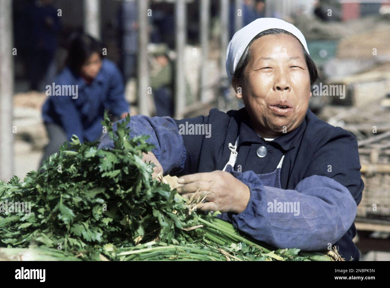 A Chinese woman sells vegetables from a stall at free market in ...