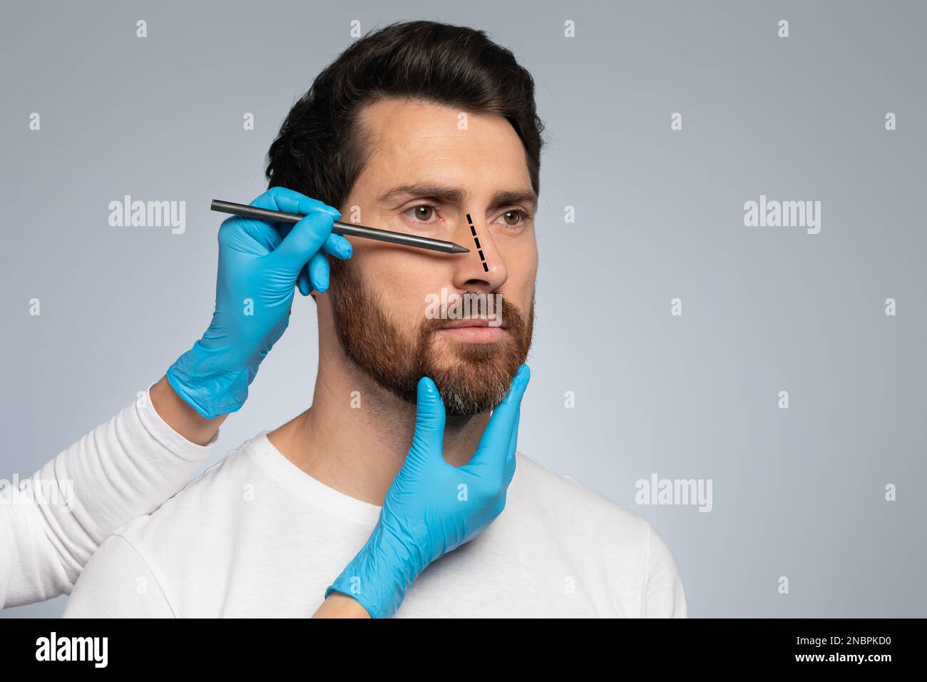Doctor in protective gloves drawing marks on man's nose for cosmetic ...