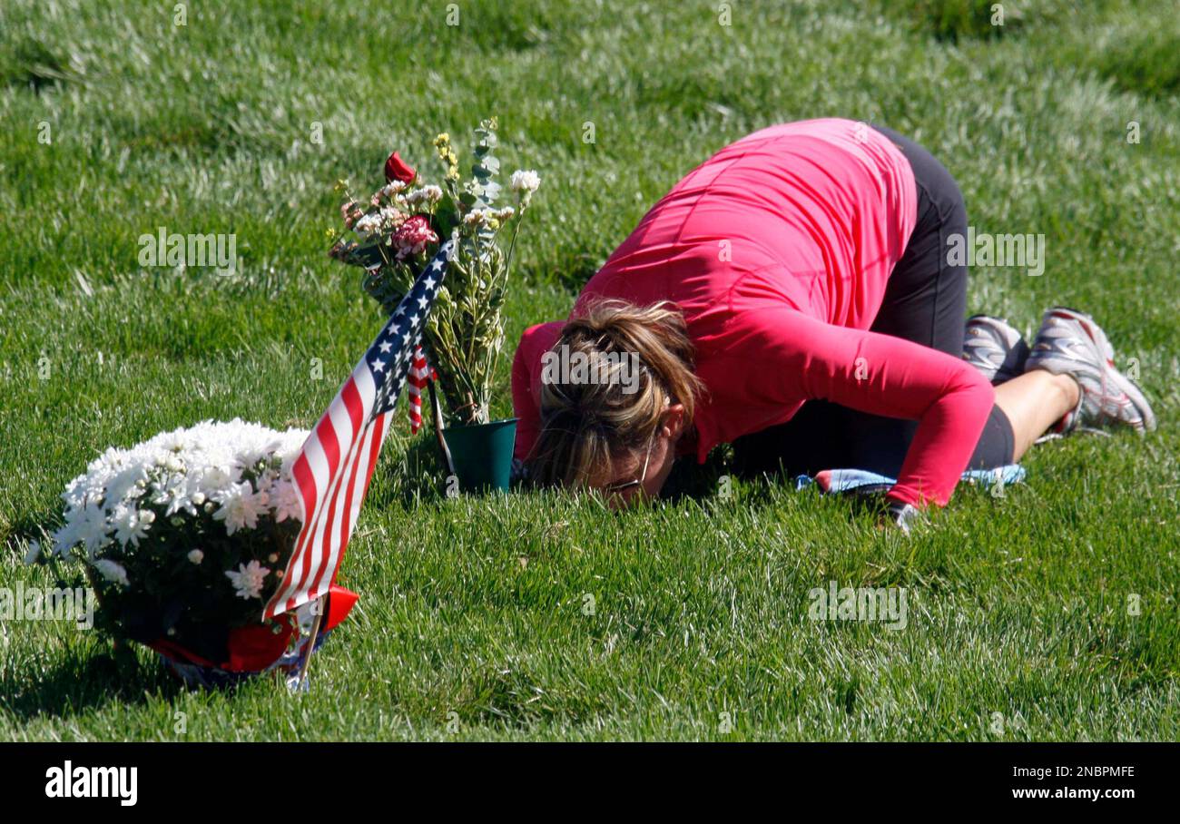 Robyn Tokar kneels at the grave of her father, Paul Tokar, who died in ...