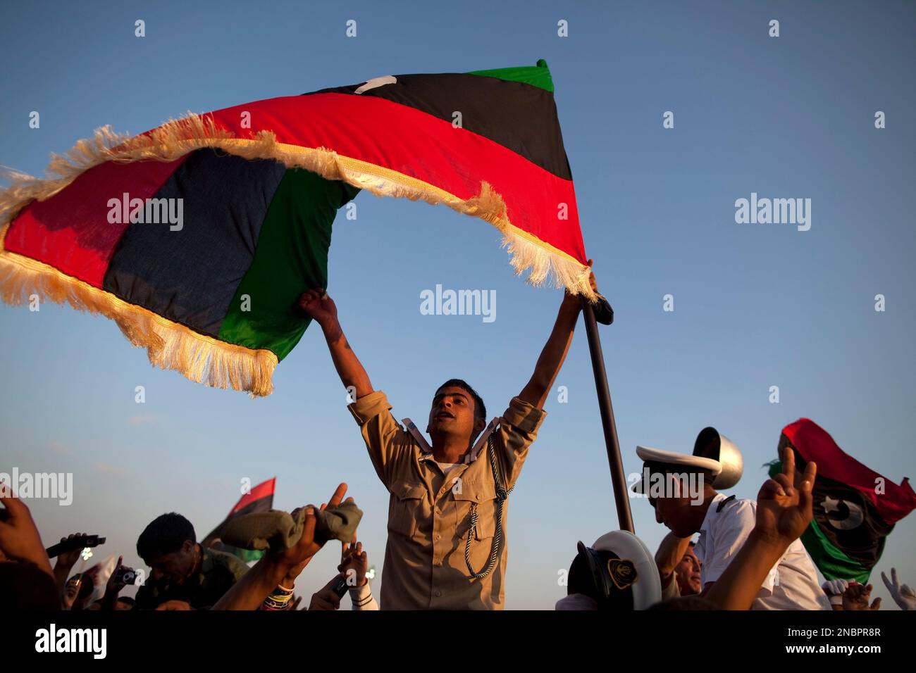 A new cadet for the Libyan rebel army holds a pre Moammar Gadhafi flag ...