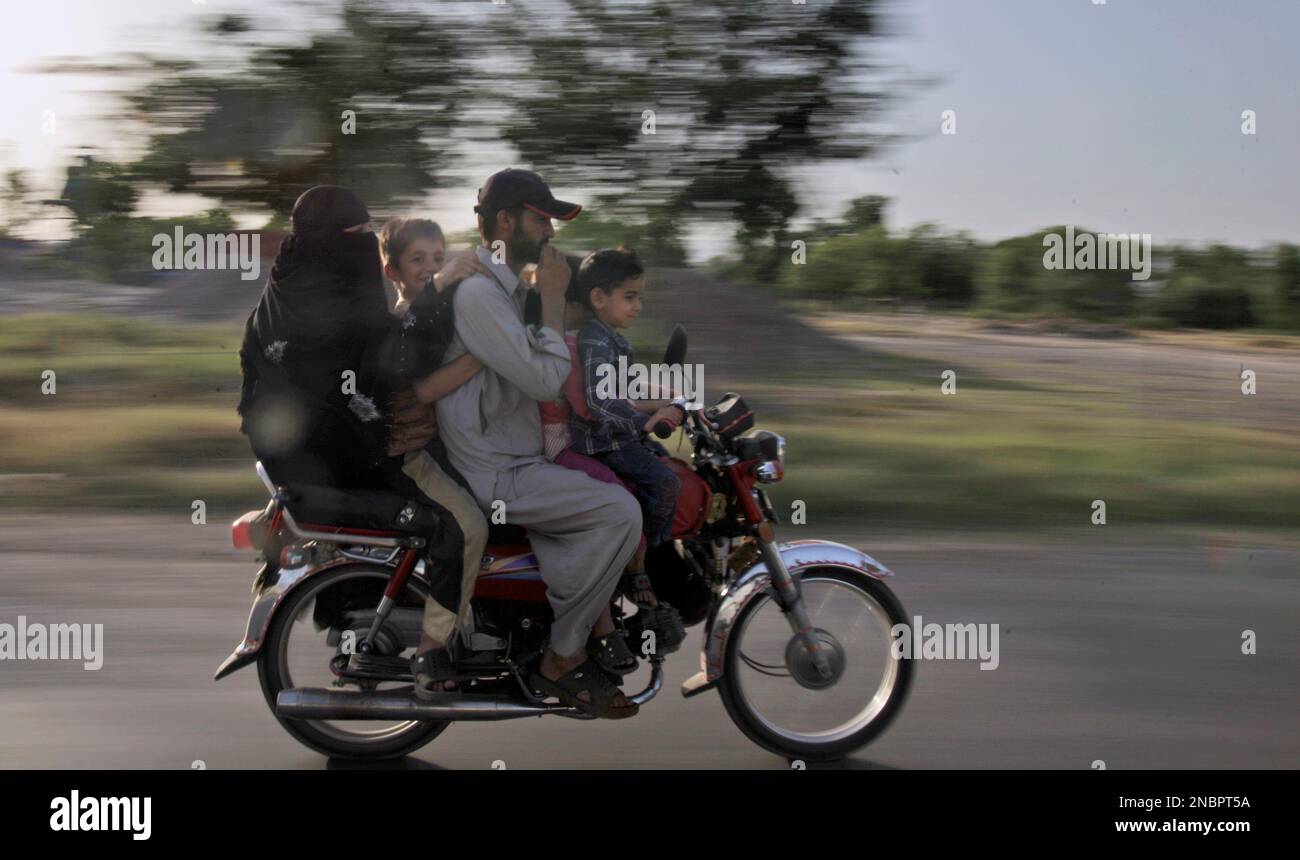 A Pakistani boy, looks on while he rides on a motorbike with his family ...