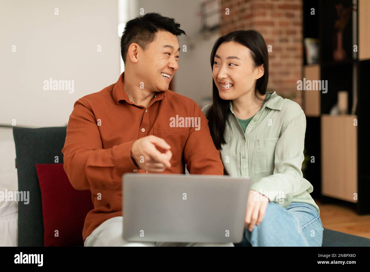 Digital entertainment. Excited asian couple using laptop at home ...