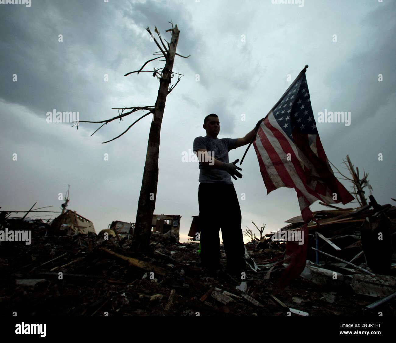 Kerry Roberts removes a tattered flag from a pole so he can fold and ...