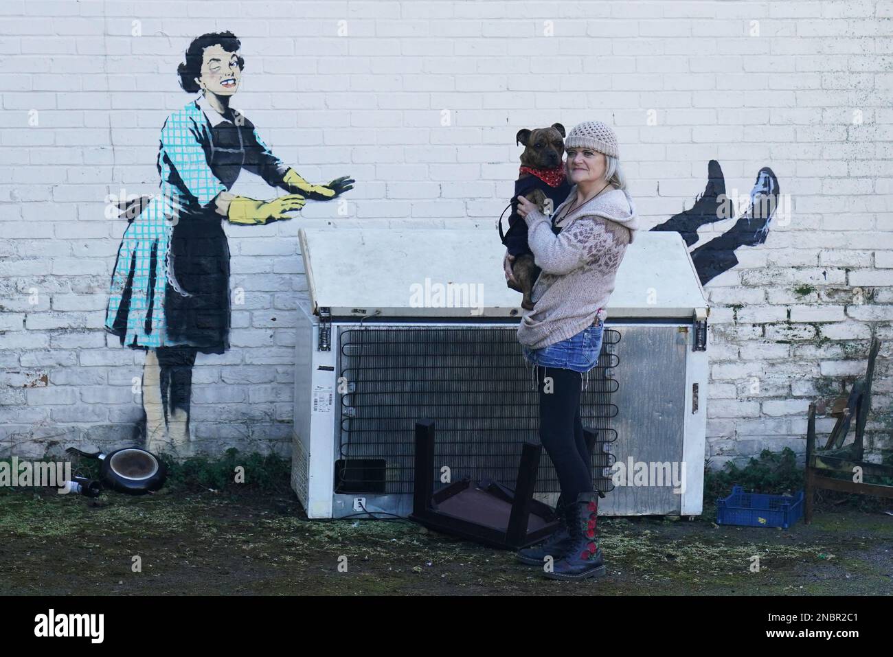 A woman and her dog pose next to a new artwork by street artist Banksy ...