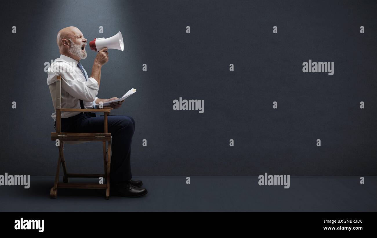 Confident professional film director sitting on the director's chair ...