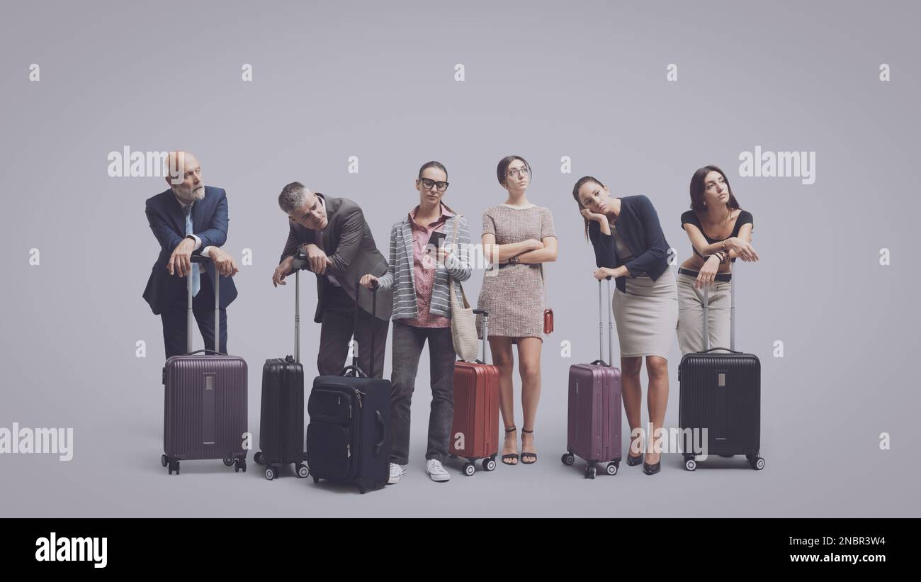 Group of tired bored travelers standing and waiting with trolley bags, travel and delays concept ...