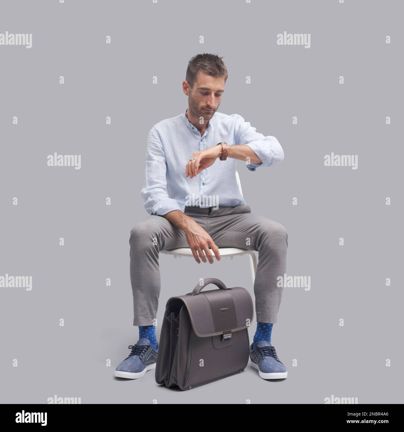 Bored man sitting on a chair and waiting for a meeting or a job ...