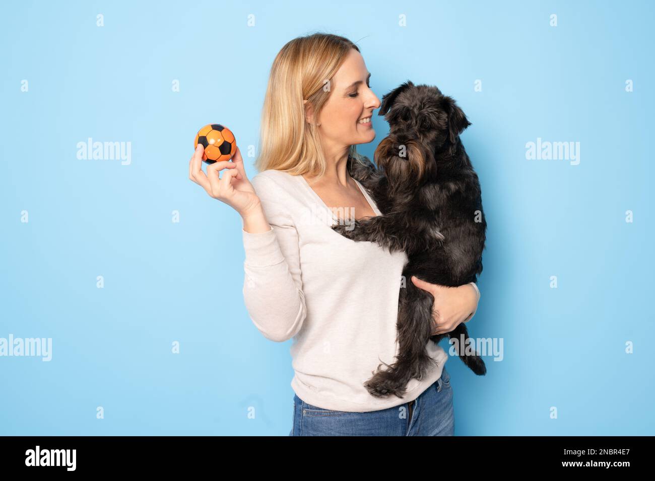 Cute young woman hugs her puppy schnauzer dog. Love between owner and ...
