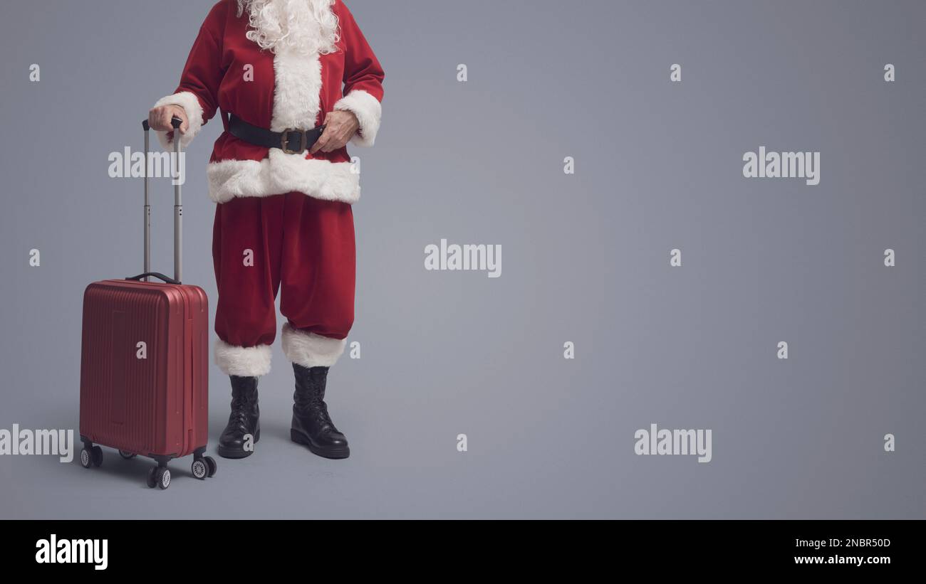 Travelling Santa Claus holding a trolley bag and waiting, he is leaving ...