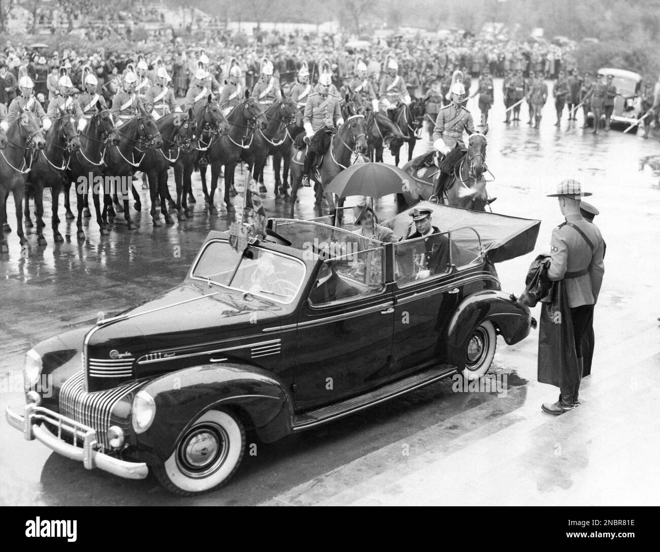 Queen Elizabeth, holding an umbrella and King George VI as their car ...