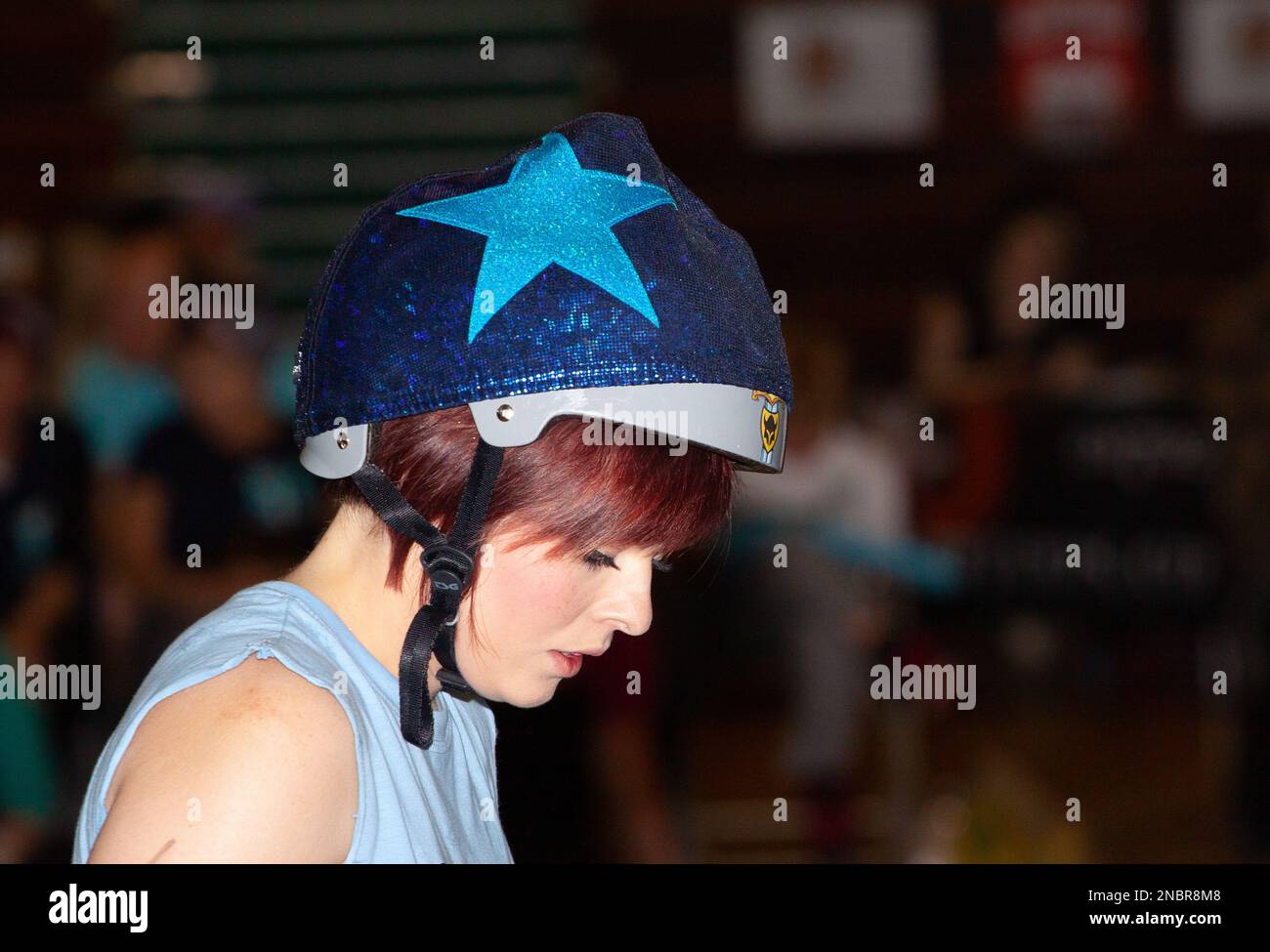 Woman skater wearing a star helmet cover as a roller derby jammer waits ...