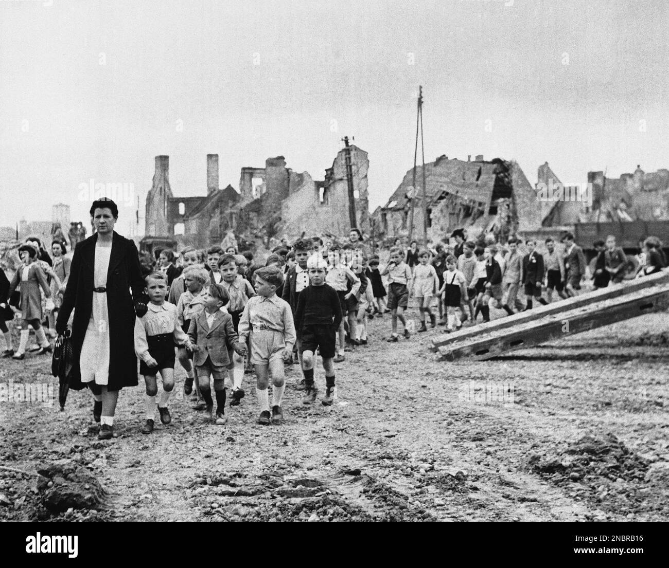 Children join the march past ruined homes in Isigny, France on July 14 ...