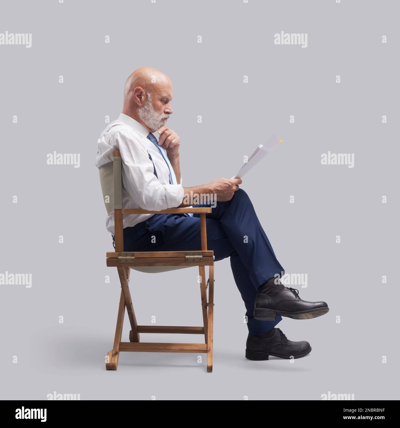 Professional actor sitting on a director's chair and reading a ...