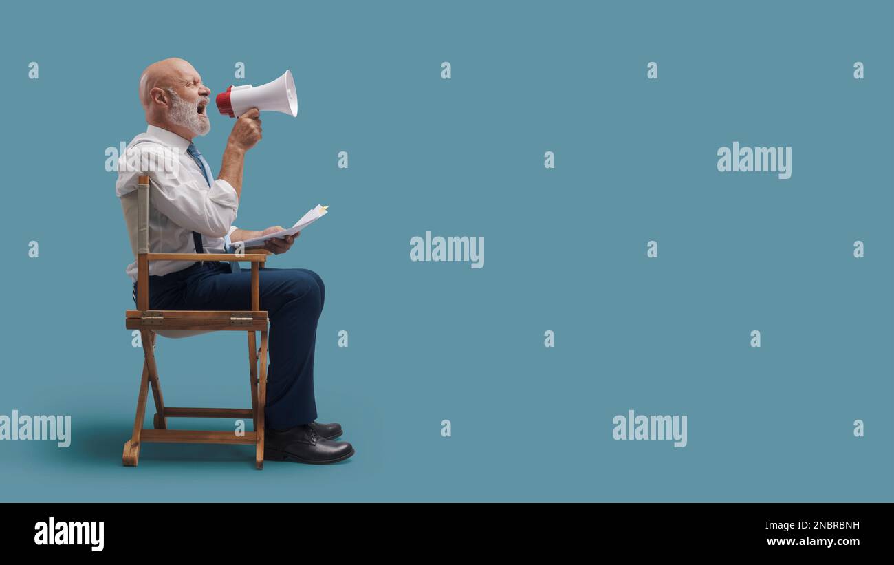 Confident professional film director sitting on the director's chair ...